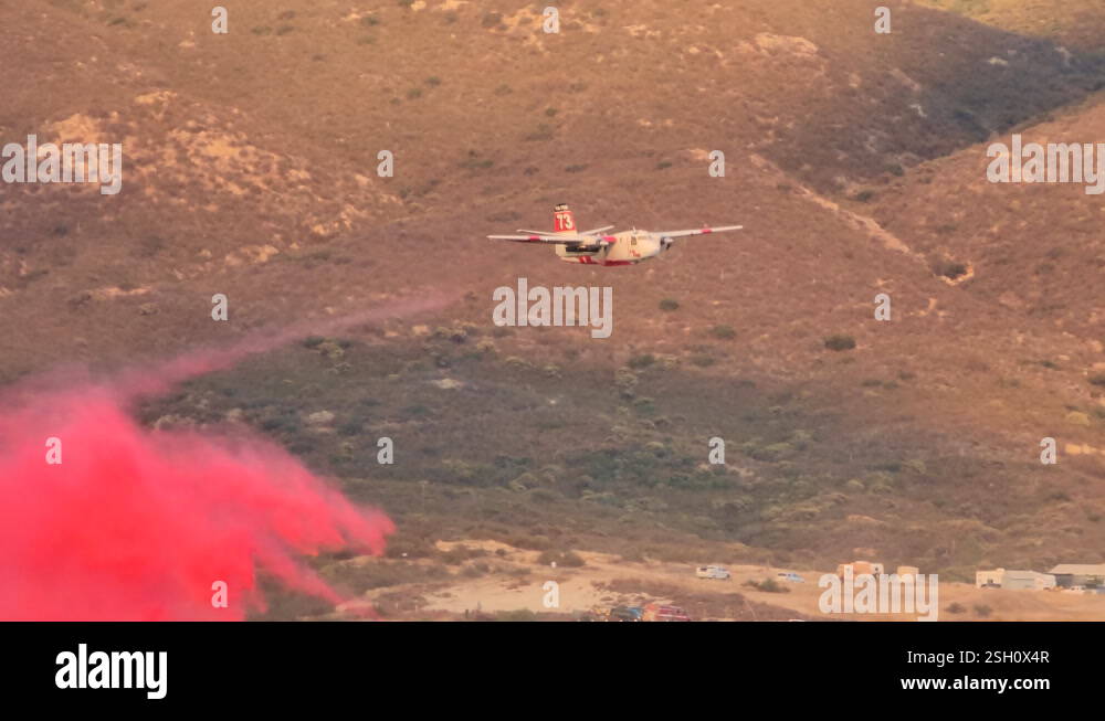 Firefighting plane drops pink chemical water at rugged hill terrain to ...