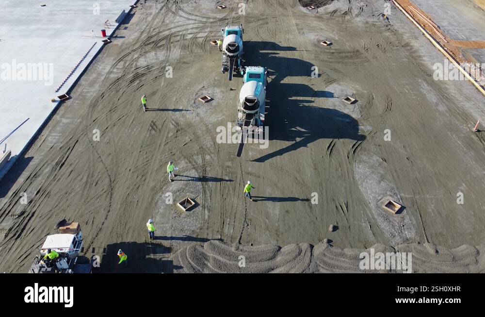 A concrete mixing truck drives away from a concrete pad it just poured ...