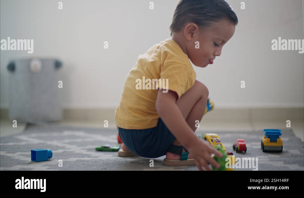 Young cute latin toddler on the floor on a grey playing alone with his ...