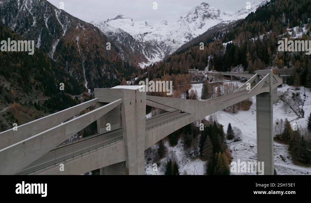 Cars drive over a bridge in the mountains. The bridge connects the ...