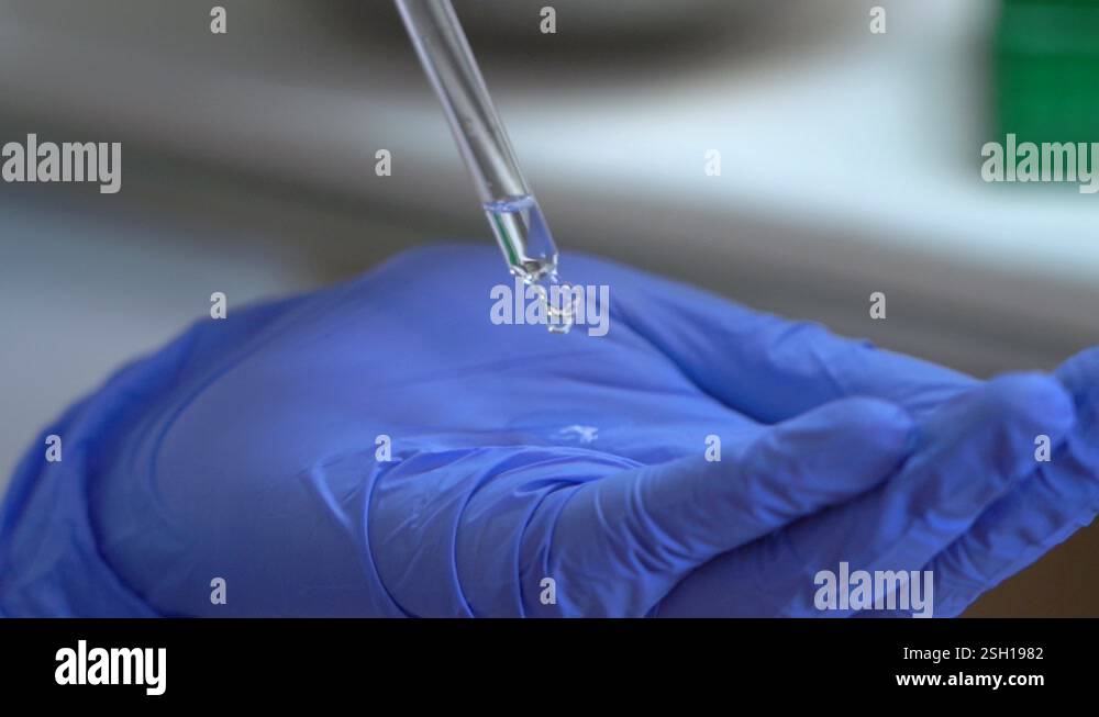 Close-up dripping a liquid into a gloved hand in a chemistry science ...