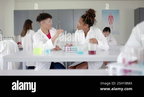 Teenage biracial boy and young biracial woman in a lab. They are ...