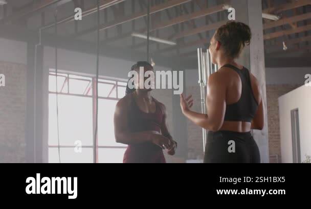 Discussing workout routine, two women in gym wearing athletic clothing ...