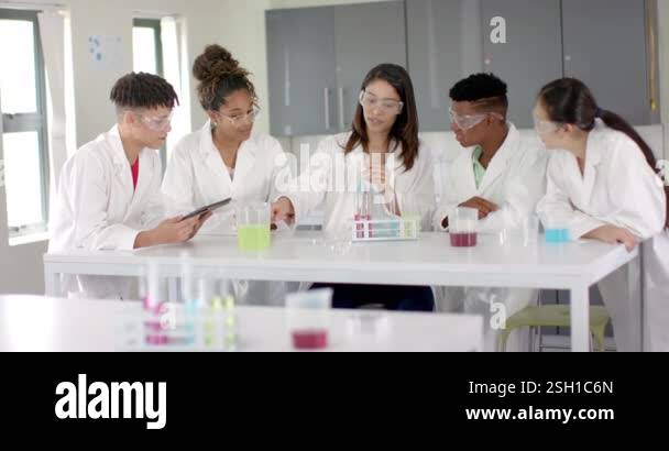 Diverse students collaborate on science experiment at high school. Teenage Biracial boys ...