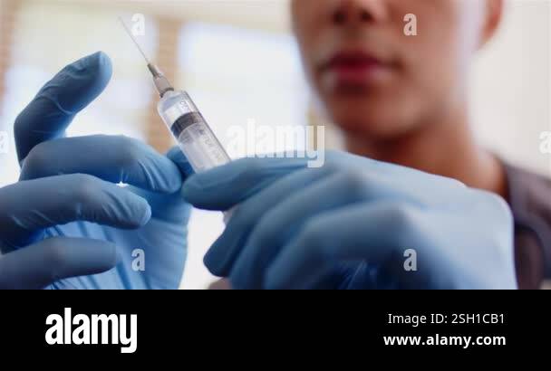 Preparing syringe for medical procedure, healthcare worker wearing ...