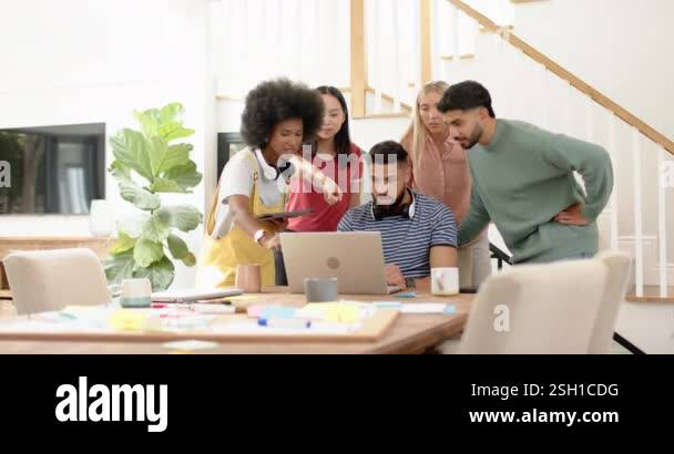 Collaborating on project, group of young diverse friends using laptop and tablet at home ...