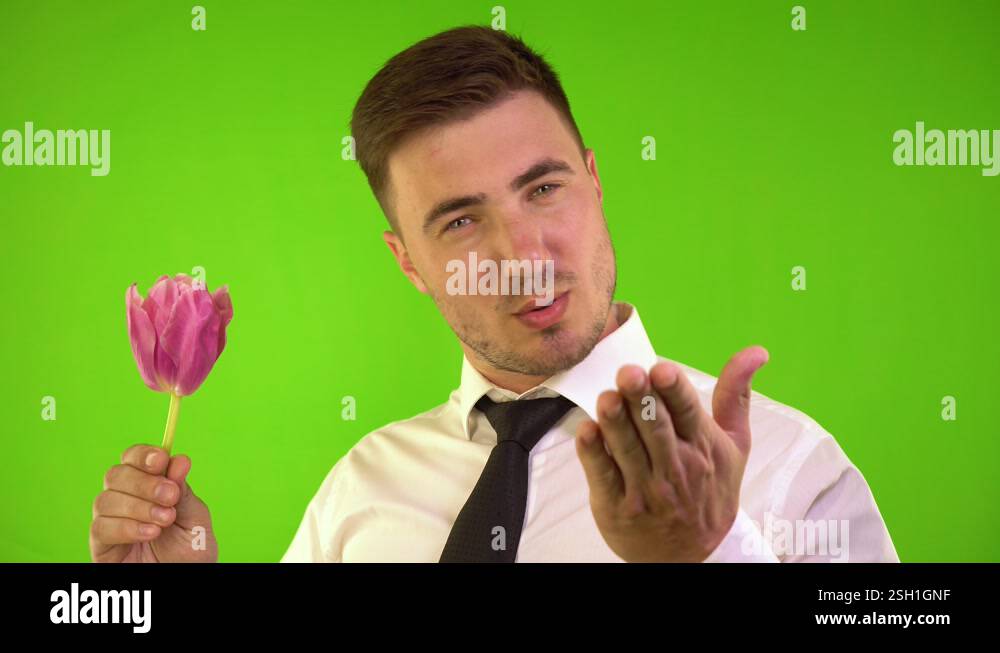 A flirting Young Man with a flower in his hand winks an eye, sends an ...