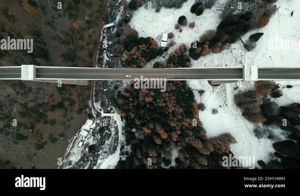 A bridge in the mountains filmed from above. Cars drive over the span ...