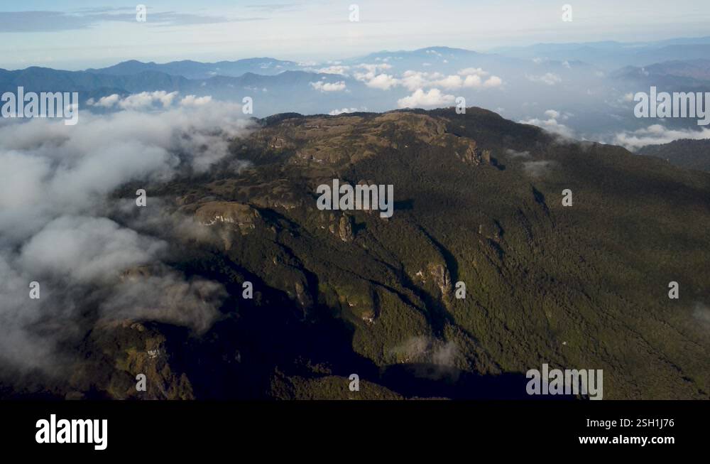 Rocky mountain peak rises above clouds, Papua New Guinea landscape ...