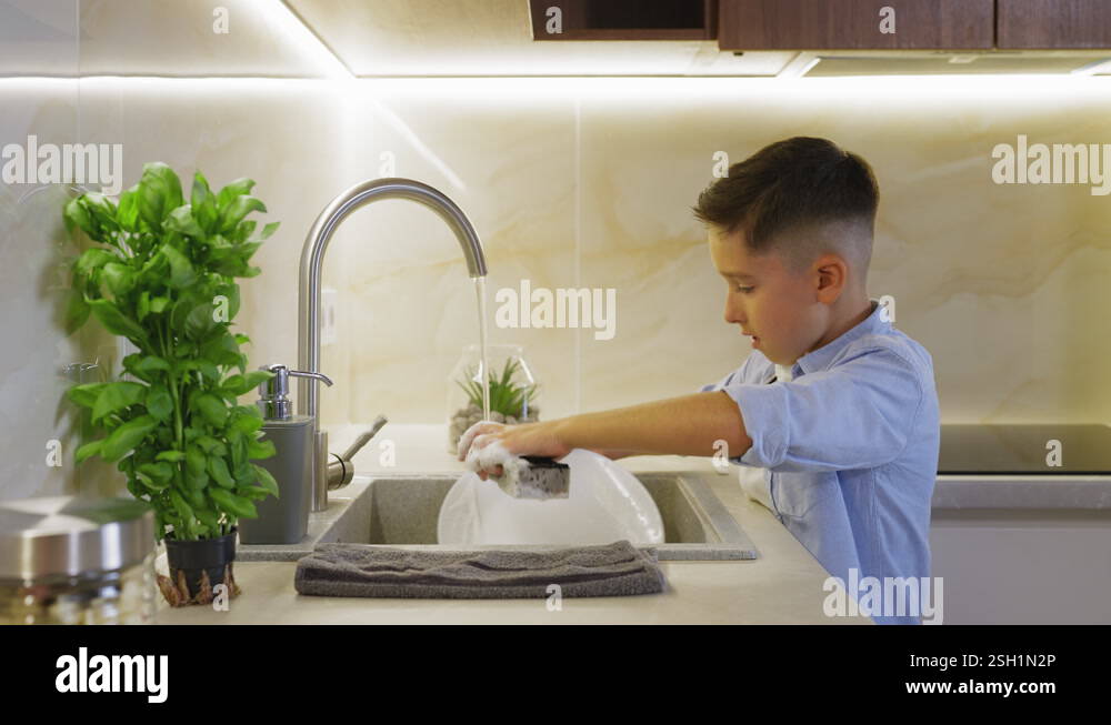 Little boy washing dishes in kitchen home, helping parents with household chores Stock Video ...