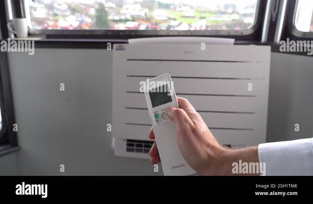 Holding up remote and turning down temperature on heat pump seen in ...