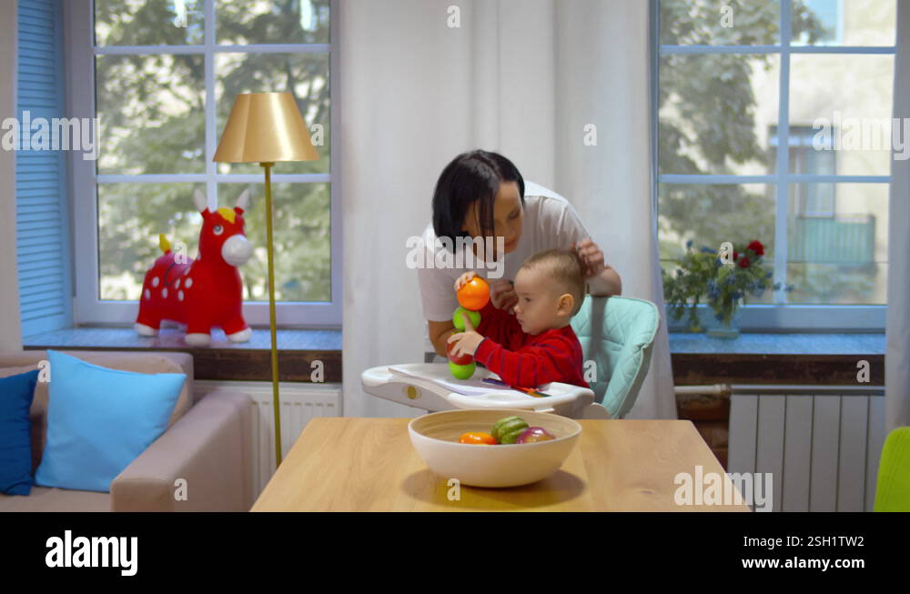 Happy young mother in modern loft apartment kiss and hug toddler son sitting on Stock Video ...