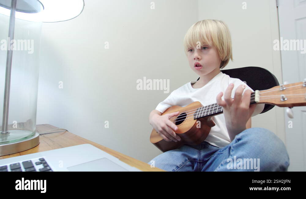 Zooming out view of 5 years old boy is having online lesson how to play ...