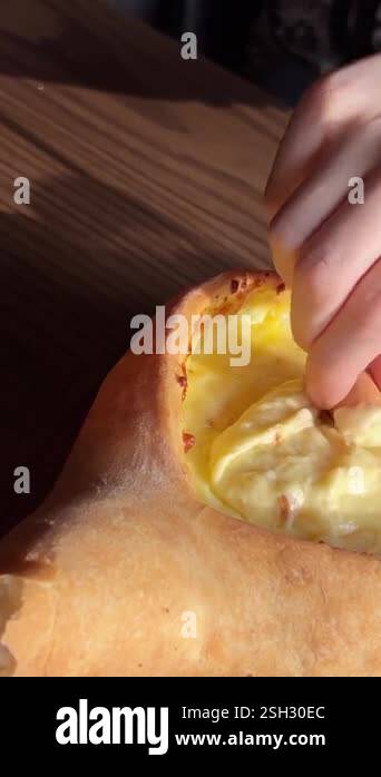 Womans hands tearing off a piece of Adjarian Khachapuri and dipping it ...
