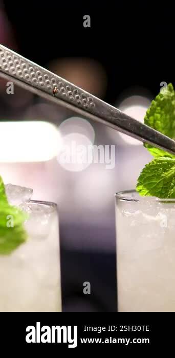 Hand adding lime slice to cocktail, refreshing drink preparation with ...