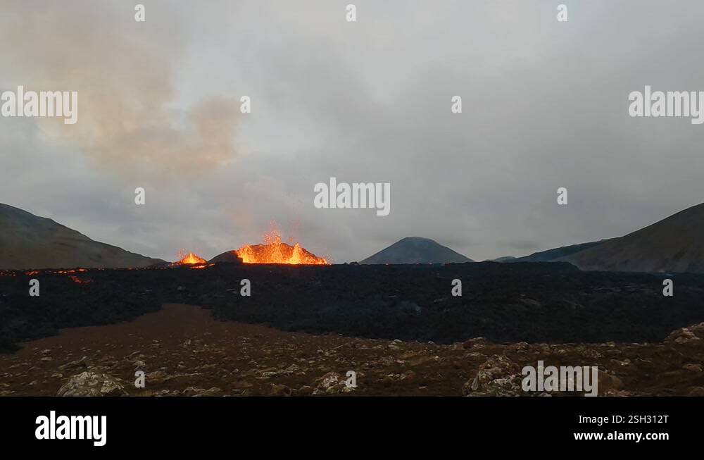 Rocky lava flow and a erupting volcano crater, bubbling earth pressure ...