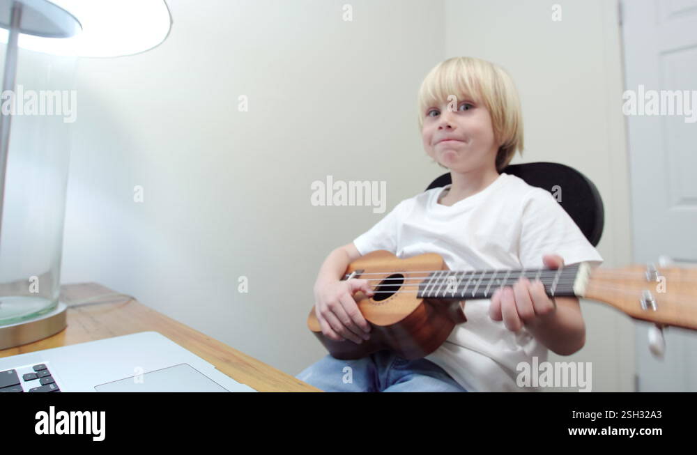 Zooming out view of 5 years old boy is having online lesson how to play ...