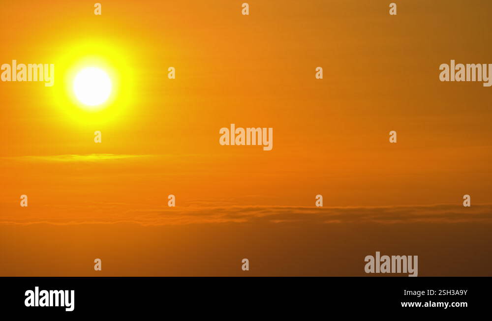 Bright, fiery, yellow sun as it descends through the sunset haze in a ...