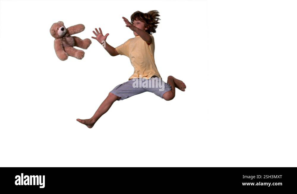 Little boy jumping up and catching teddy bear on white background Stock ...