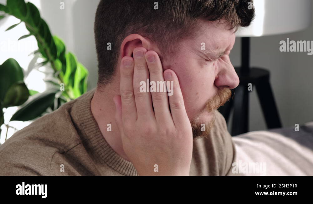 Unhealthy young man touching ear, suffering from sudden throbbing ear ...