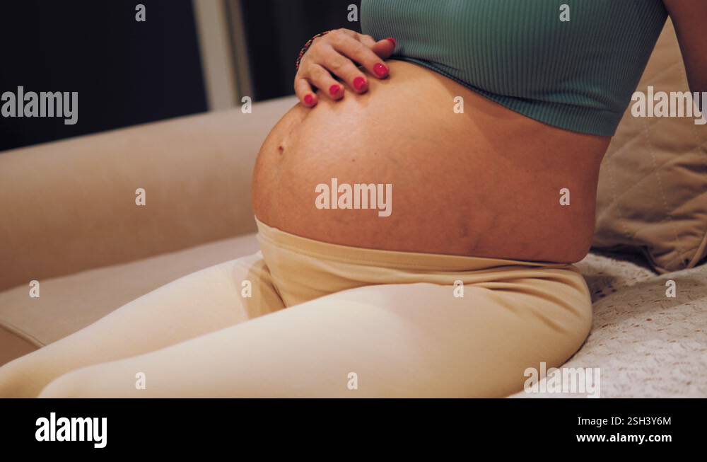 Unrecognizable pregnant woman stroking her big belly with affection ...