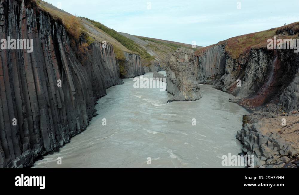 Aerial down glacial river with dramatic basalt rock columns, Studlagil ...