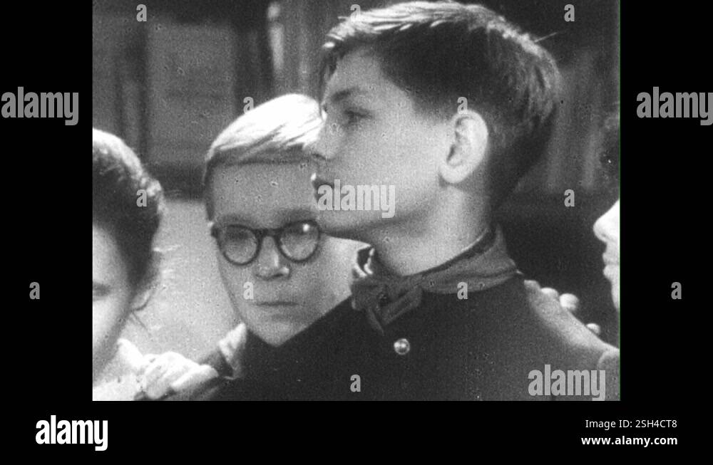 1940s: Students look accusingly at boy. Boy lowers head in shame ...