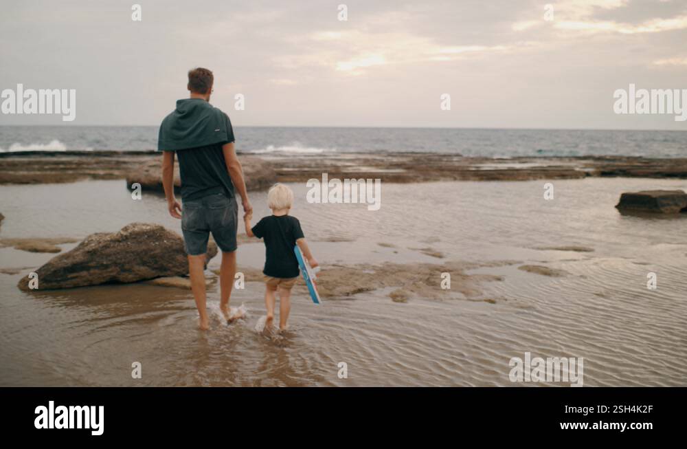 Father and son walking sea water beach admiring nature scenery holding ...