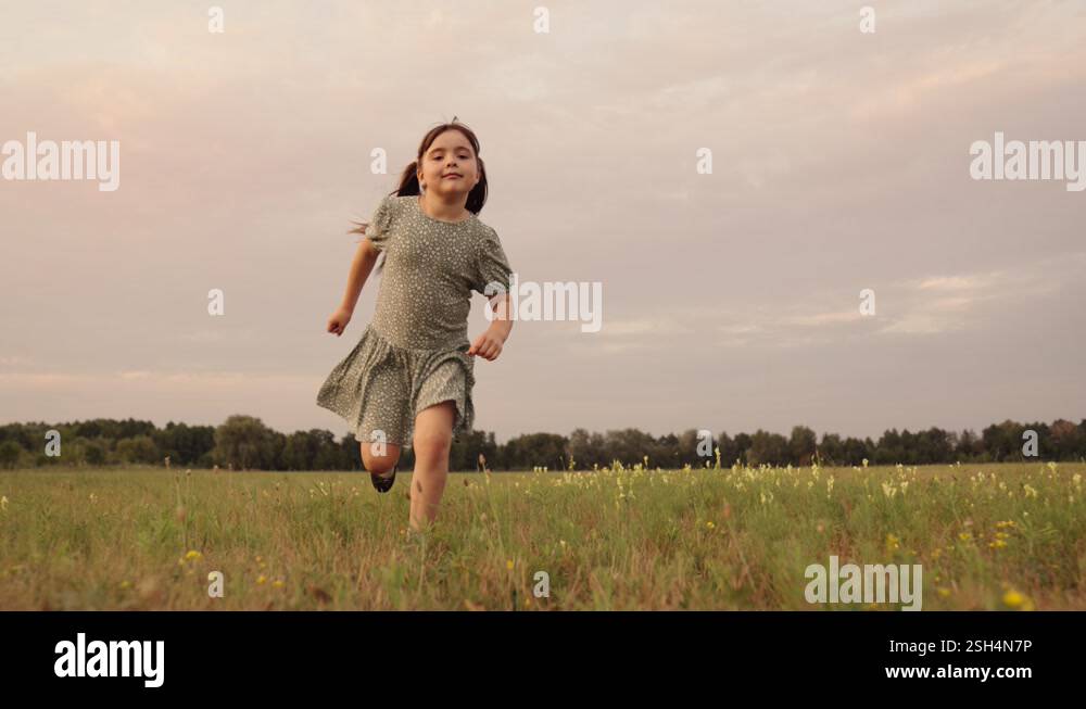happy little girl runs across green field. cheerful child kid run ...