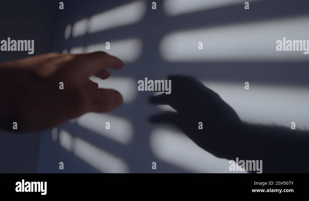 Dramatic hand move touching and moving over a wall with window blind ...