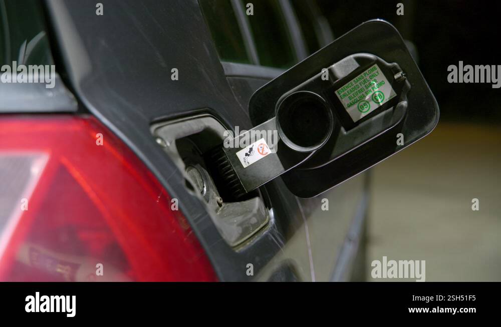 Ppening the fuel filler flap in the car on a petrol station at night ...
