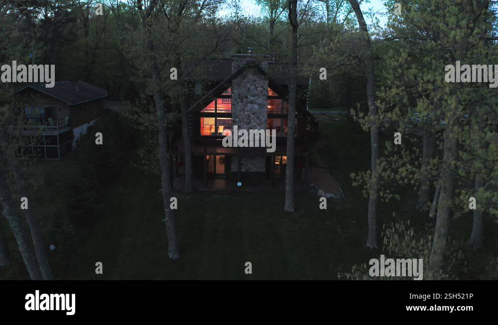 Aerial, expensive luxurious cabin in the forest in the evening. Lights ...