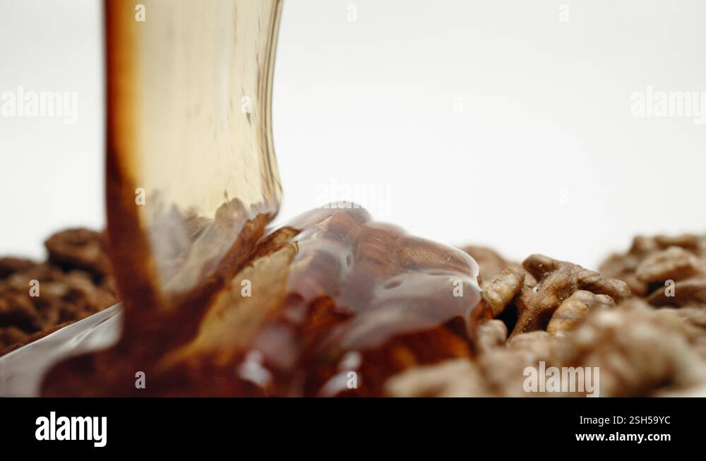 Honey pouring walnuts on white background slide shot. Caramel flowing ...