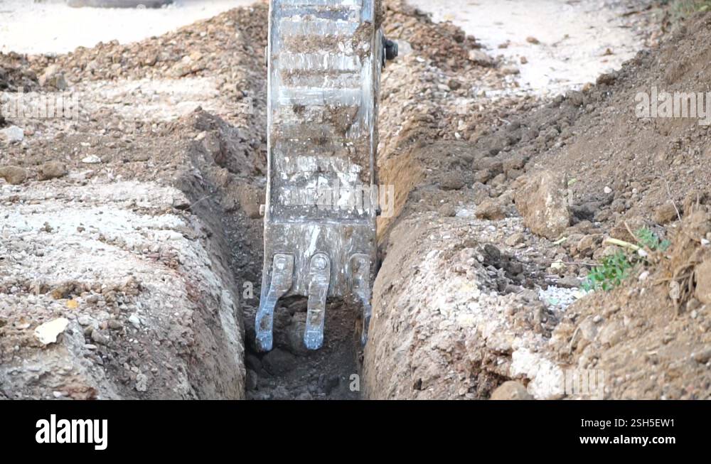 Excavator digs a trench to lay pipes. Close up of an excavator digging ...