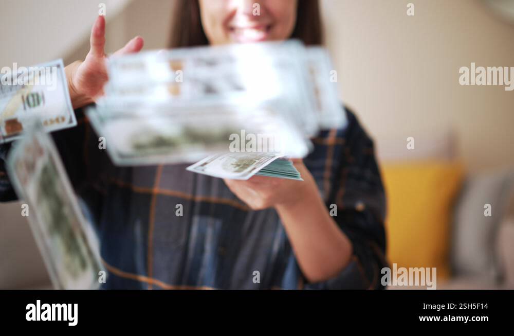 Young woman enjoy, smiling, holds stack of money in hand, flips through ...