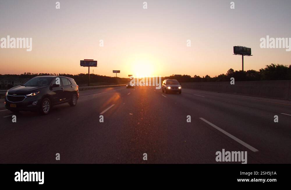 rear view POV FPV driving on a highway sun beaming on horizon exit ramp ...