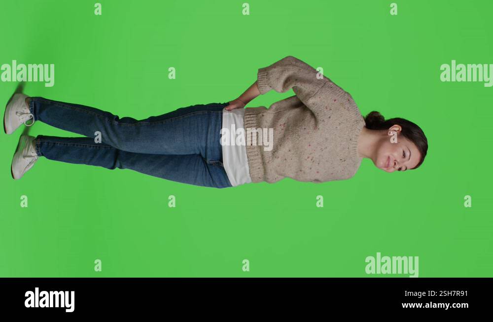 Vertical video: Side view of caucasian girl posing on full body green ...