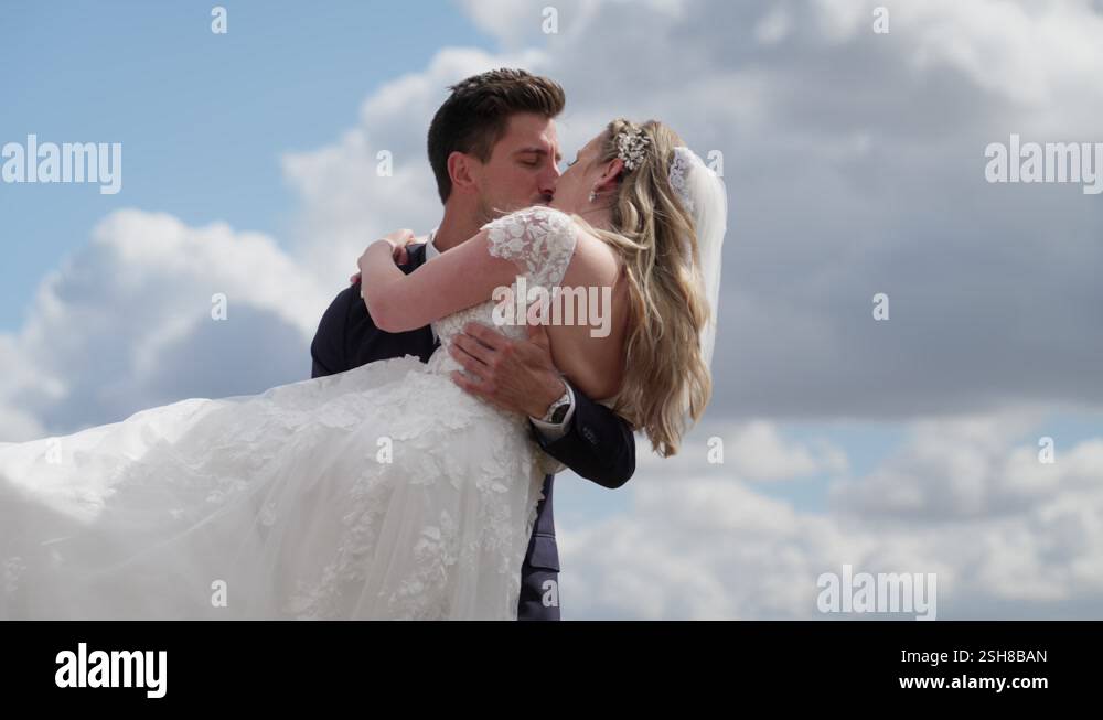 Loving husband carrying his new wife while kissing her and showing ...