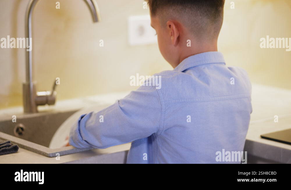 Little boy washing dishes with soapy water, helping out with household ...