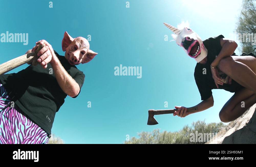 Two killers in horse and pig masks pose threateningly with axes and ...