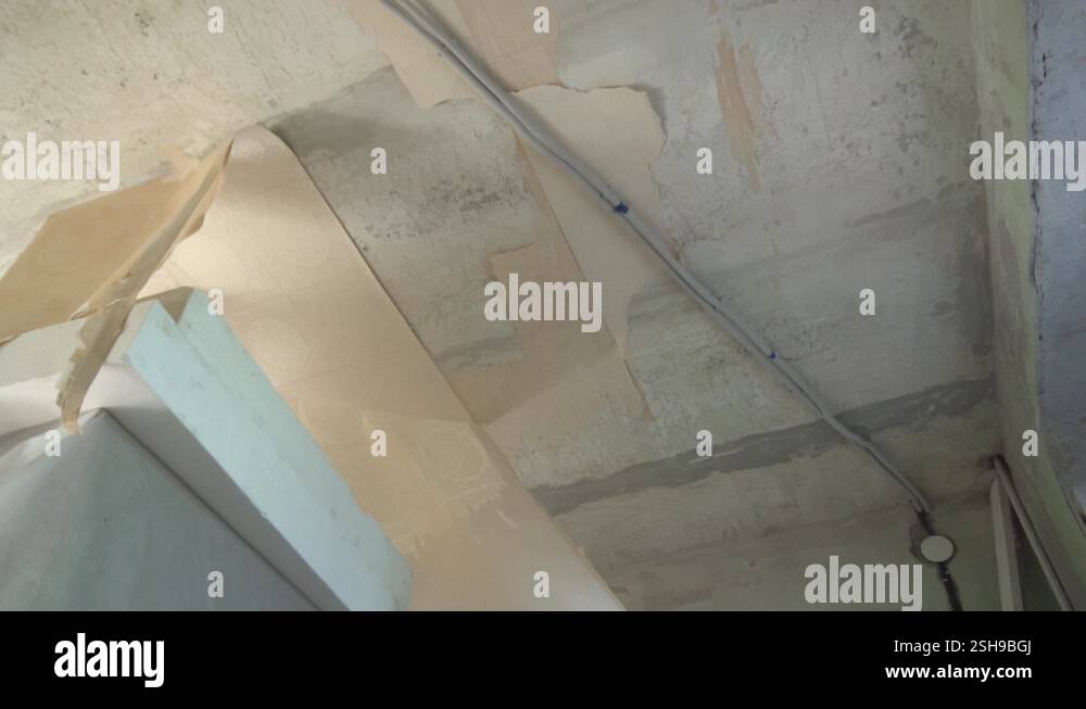 Process of removing old decrepit wallpaper from the ceiling of the room ...