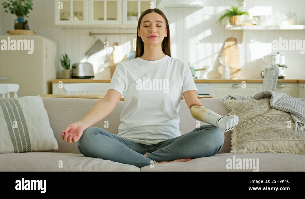 Calm young girl with artificial hand prosthetic meditates in lotus pose ...