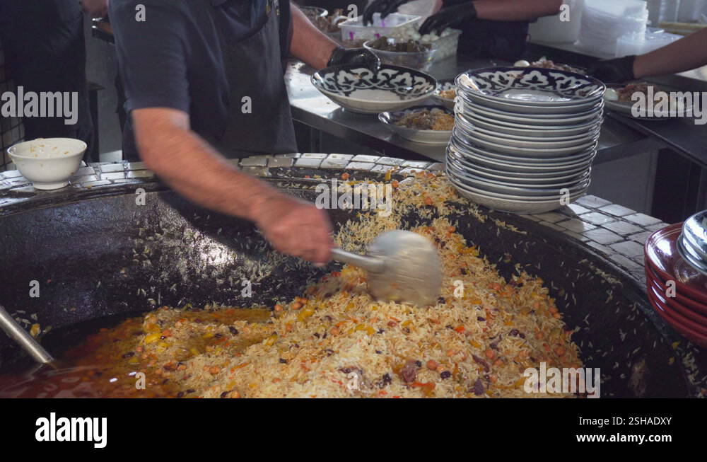 Cookers are putting plov (pilaf) on plates, Tashkent, Uzbekistan Stock ...