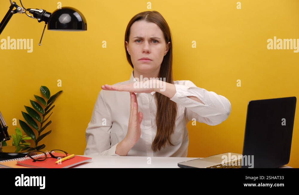 Strict woman sitting work at office desk with laptop holding stop ...