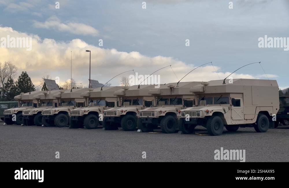 Tan military vehicles in a row with clouds rolling in the back Stock ...
