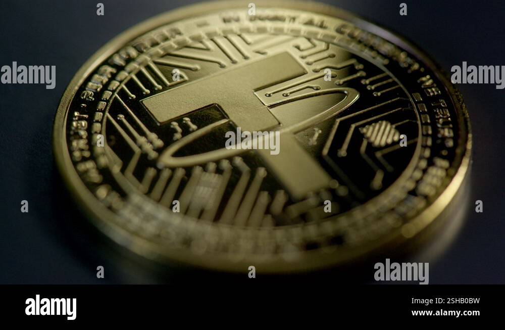 A physical golden USDT Tether coin lying on the dark background with a ...