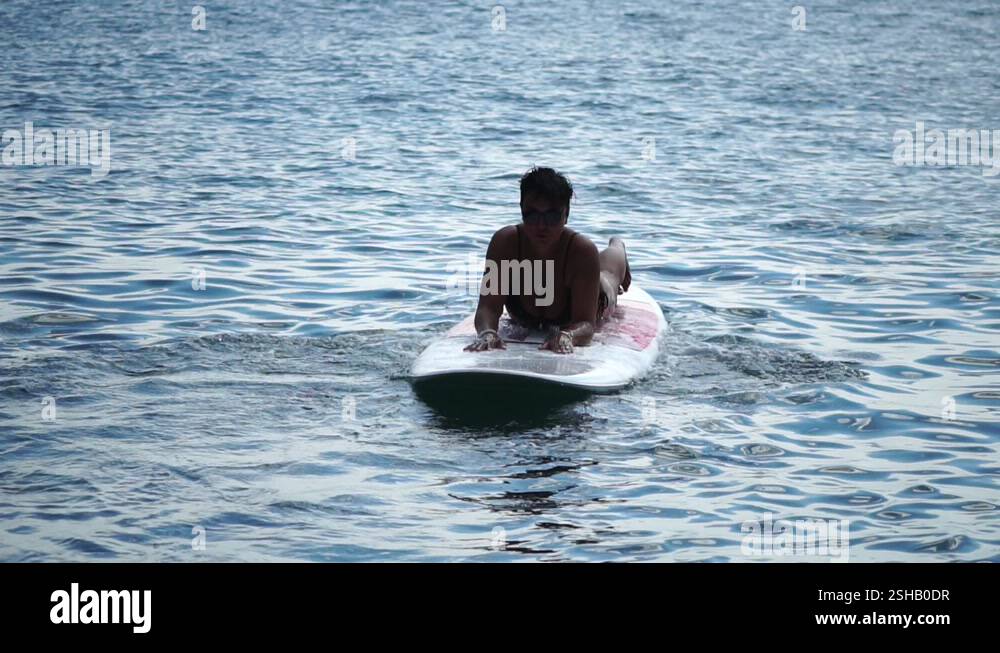 Happy body positive woman smiling and paddling on her surfboard in ...