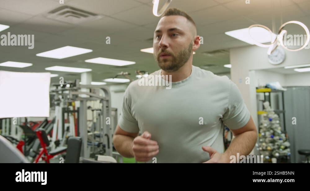 Young athletic man exercising and running on treadmill in sport gym ...