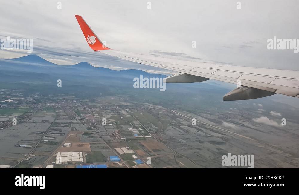 Lion Air plane flying above rural town on Indonesia, window view Stock ...