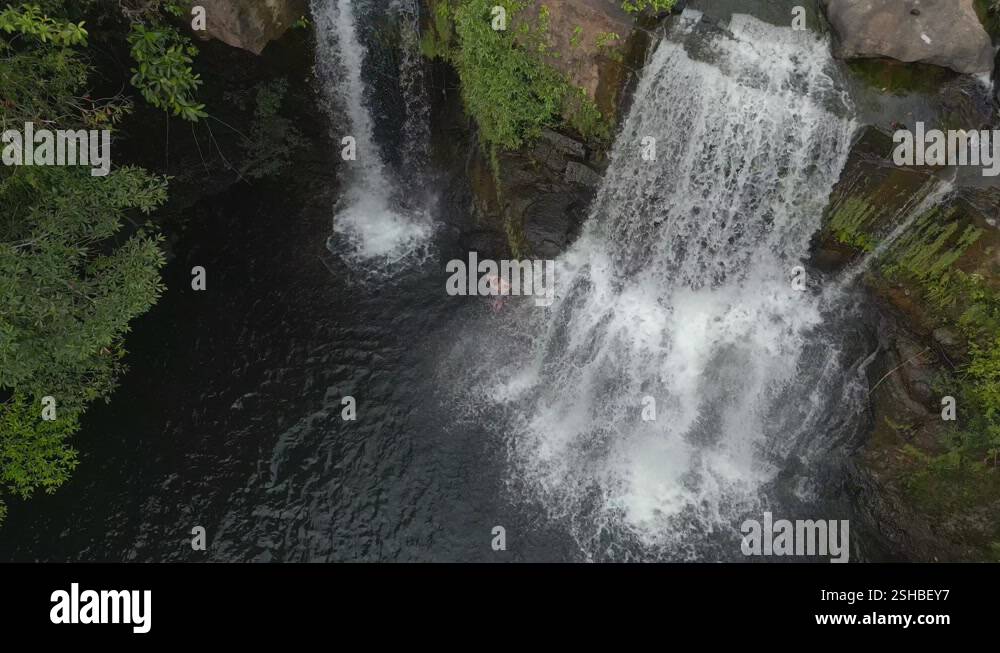 man stand under waterfall. Wonderful aerial view flight tracking shot ...